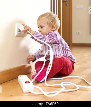 Baby girl playing with electrical extension Stock Photo - Alamy