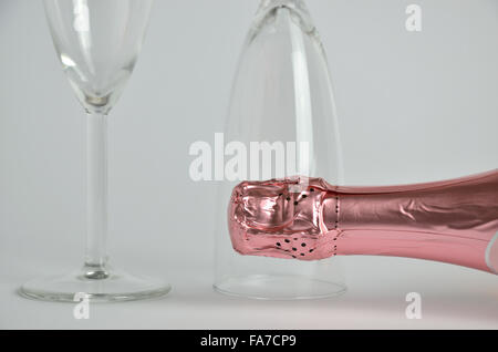 Pink champagne bottleneck with two champagne glasses in background ...