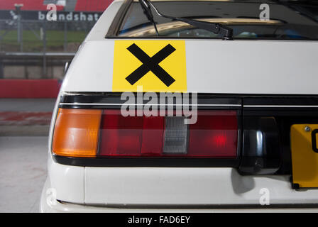 Novice sticker on a car at a race track, black X on yellow square warns ...