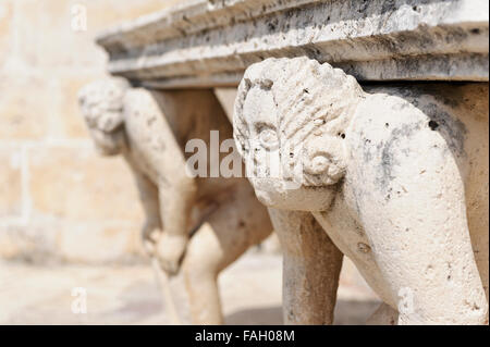 A medieval stone table is supported by two statues of the hunched men ...