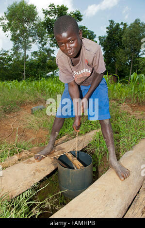 Child drawing water from a deep well with bucket and rope, Kenya Stock ...