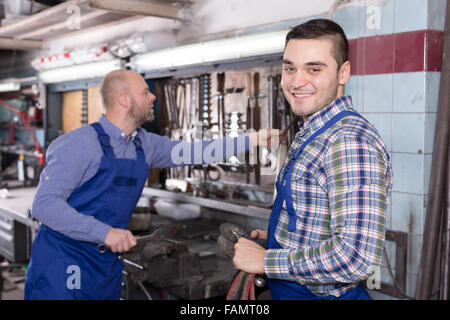 Two happy positive mechanics working in the workshop Stock Photo - Alamy