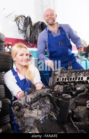 Handsome smiling russian mechanic and female assistant working at auto ...