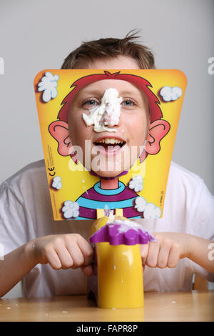 A boy playing the board game Pie Face by Hasbro getting covered in ...