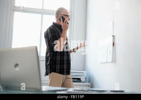 Man use smartphone and laptop in office or at home. Side view shot of ...