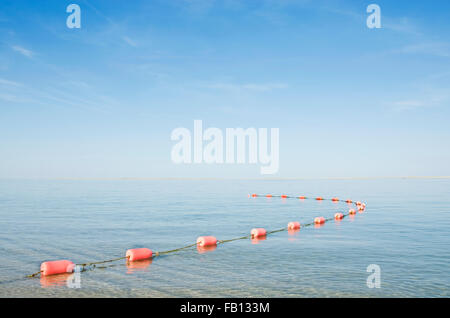Buoys on a rope in sea water. The lifebuoys are pink restraints to ...