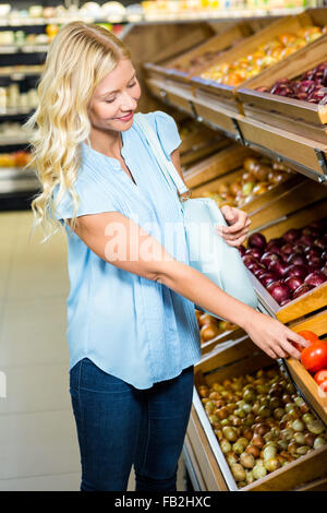 Smiling young woman choosing tomatoes in grocery store Stock Photo - Alamy
