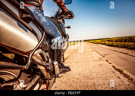Biker riding a motorcycle. Bottom view of the legs in leather cowboy ...