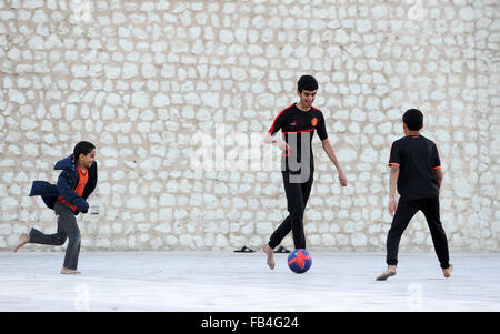 Children play soccer next to a wall painted with the flags of countries ...