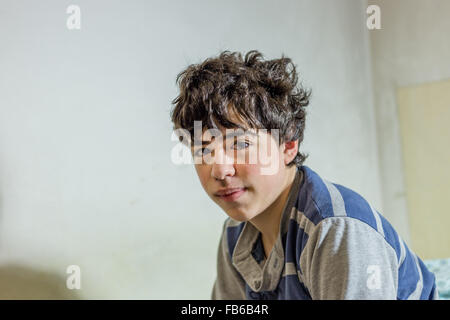 disheveled caucasian boy in blue coat looking at camera calm and ...