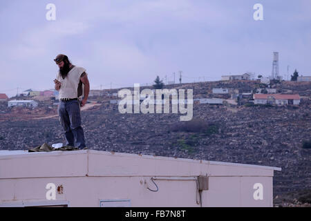 A religious Jewish settler repairs the roof of his temporary home in ...