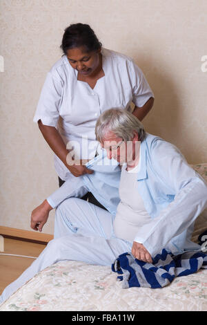 Nurse helping patient get dressed Stock Photo - Alamy