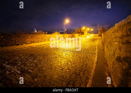 Cobbles among stone walls illuminated by lights at night Stock Photo ...