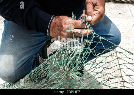 hands of fisherman with nets and knife for repair Stock Photo - Alamy