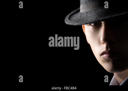 Mysterious man in hat with half of his face in the shadows ...