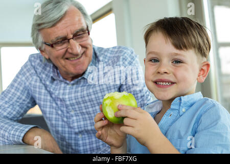 Grandson and grandfather eating apple together bonding at living room ...