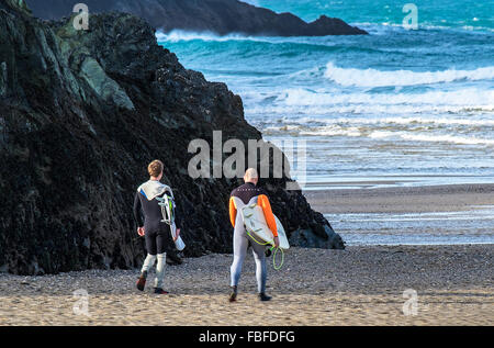 Two surfers walking in the sea at Fistral Beach on the coast of Newquay ...