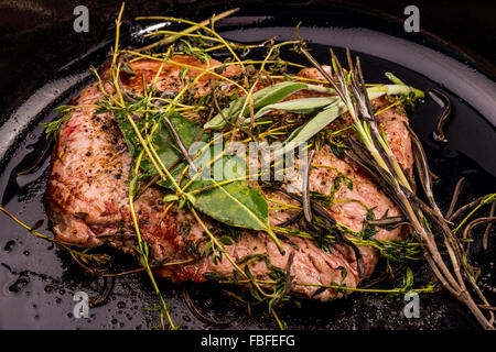 Fried beef steak with herbs in frying pan on wooden table Stock Photo ...