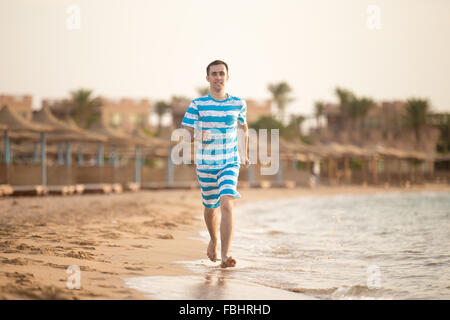 Man working on the beach. Attractive man with laptop seated in a palm ...