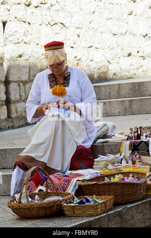 A woman doing some needlework and selling her finish work in Old Town ...