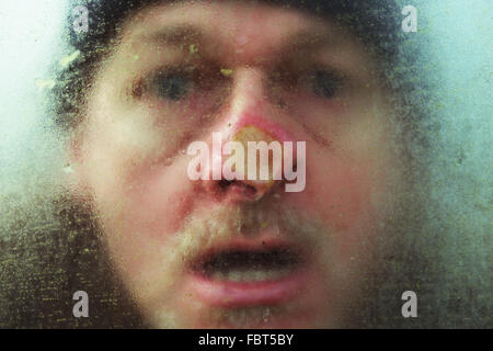 Man with face pressed up against window, studio shot Stock Photo - Alamy