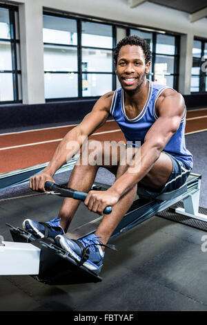 smiling man using rowing gym machine Stock Photo - Alamy