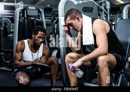 Muscular man discussing performance with trainer Stock Photo - Alamy