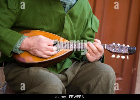 Senior man playing mandolin outside on the green background Stock Photo ...