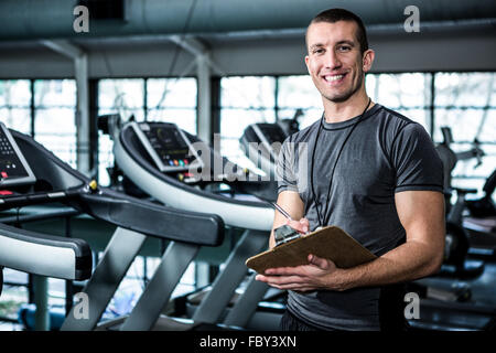 Muscular trainer writing on clipboard Stock Photo - Alamy