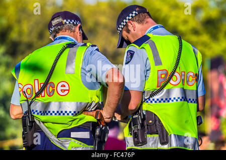 Australian police officers in uniform stood beside two Holden police ...