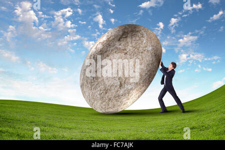 An image of a man rolling a rock uphill Stock Photo: 33940973 - Alamy
