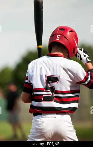 Teen baseball player from behind holding a bat at home plate during a ...