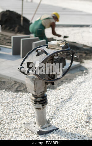 man puts the concrete tiles on the path Stock Photo - Alamy