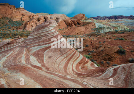 Dark ominous clouds glide past the swirling red rock striations of ...