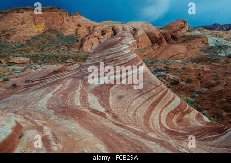 Dark ominous clouds glide past the swirling red rock striations of ...