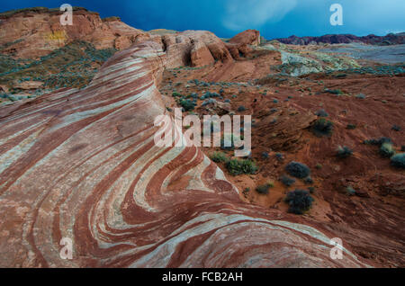 Dark ominous clouds glide past the swirling red rock striations of ...
