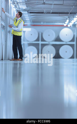 Worker checking paper in printing press workshop Stock Photo - Alamy