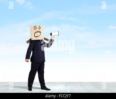 Businessman with box on head screaming in megaphone Stock Photo - Alamy