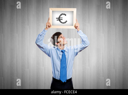 Handsome man holding frame with euro sign Stock Photo - Alamy