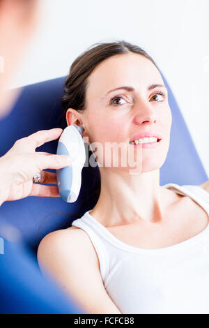 General practice doctor using an aural thermometer to measure the ...
