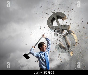 Young businessman crashing with hammer stone dollar symbol Stock Photo ...