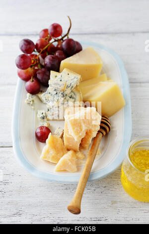 Close-up of various cheese with grapes on wooden board, copy space ...