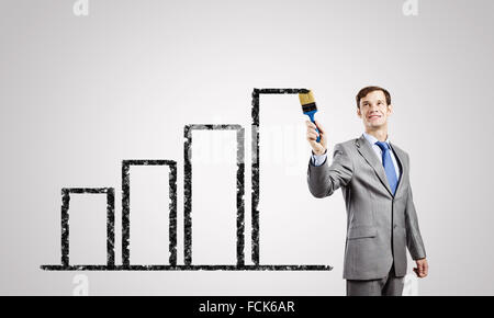 Young businessman painting graphs and diagrams with brush Stock Photo ...
