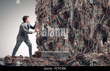 Businessman making effort to move stone wall Stock Photo - Alamy