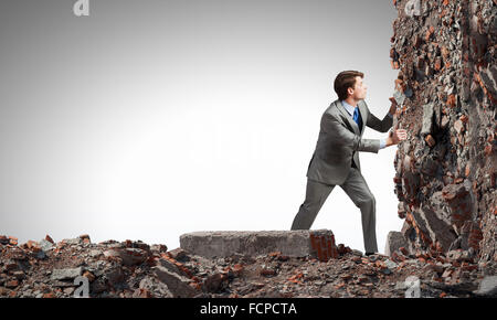 Businessman making effort to move stone wall Stock Photo - Alamy