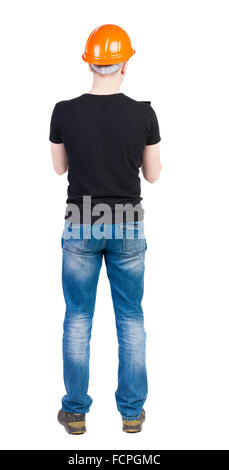 Backview of an engineer in construction helmet stands. Standing young ...