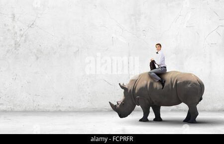 Young handsome fearless man riding huge rhino Stock Photo - Alamy