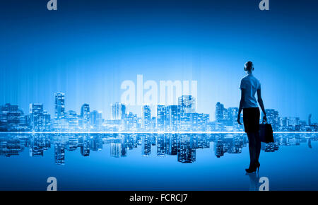 Businesswoman standing with back against night city panoramic view ...