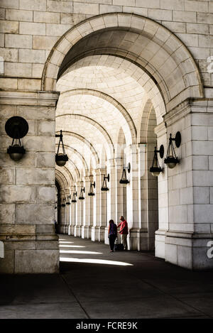 A covered stone colonnade with repeating arches stretches through the ...