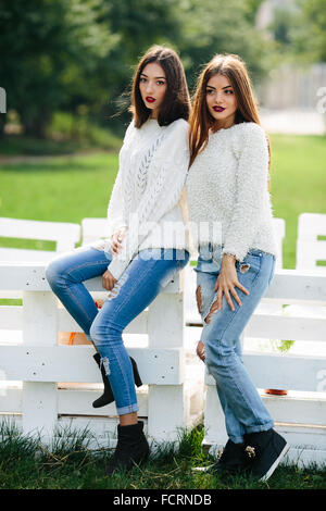 Two girls lean bench Stock Photo - Alamy